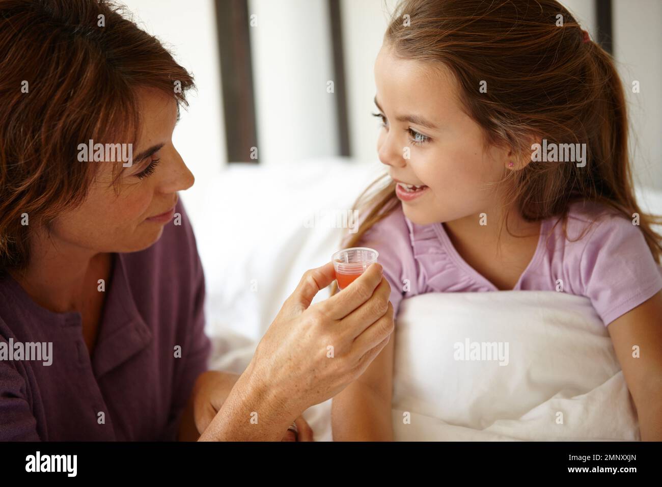 Is this going to make me better. a mother giving her daughter medicine ...