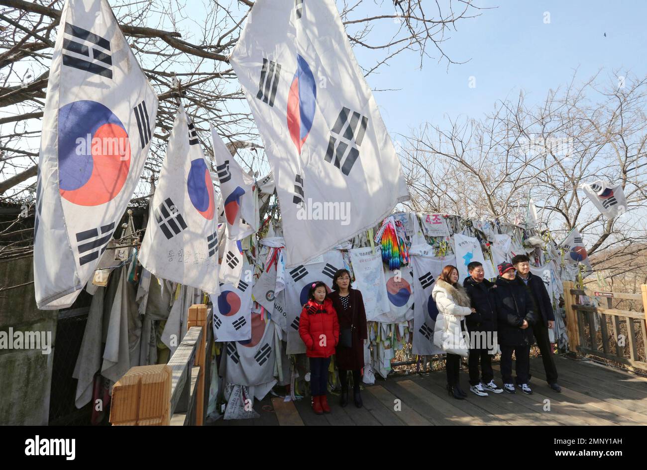 People pose in front of a wire fence decorated with ribbons, South ...