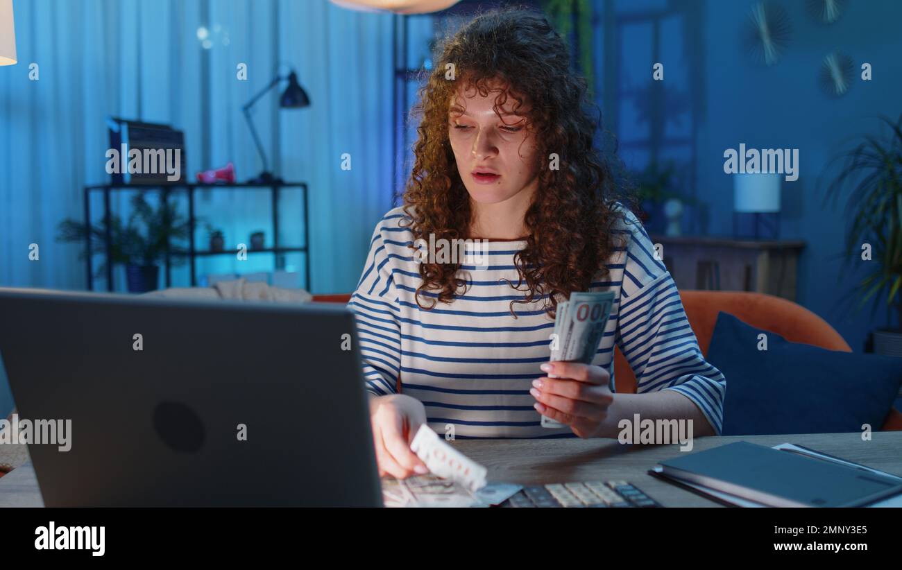 Planning budget. Rich young woman sitting at the desk counting money ...