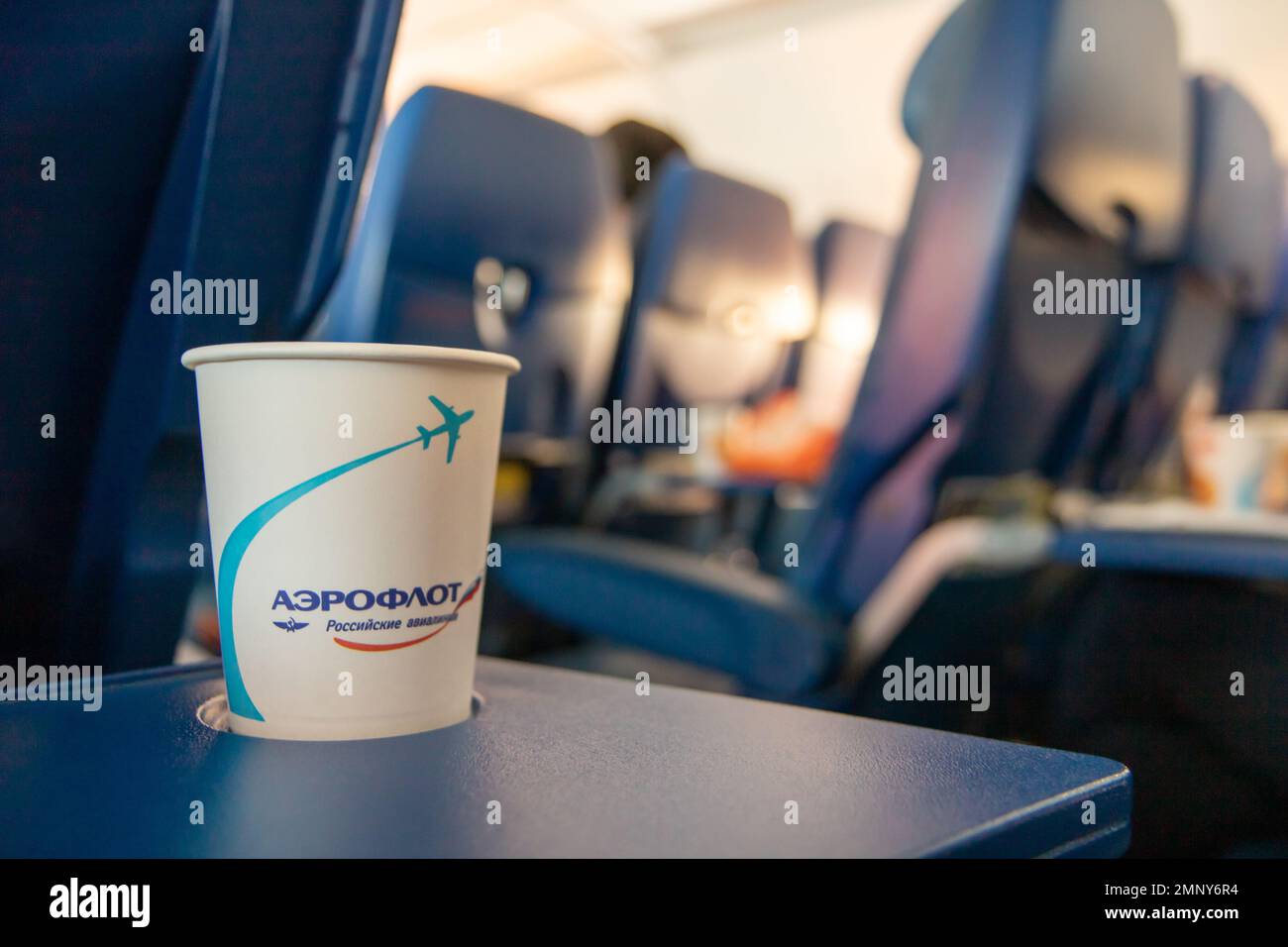 A cup with a beverage on a table in a flying plane. Refreshment with a ...