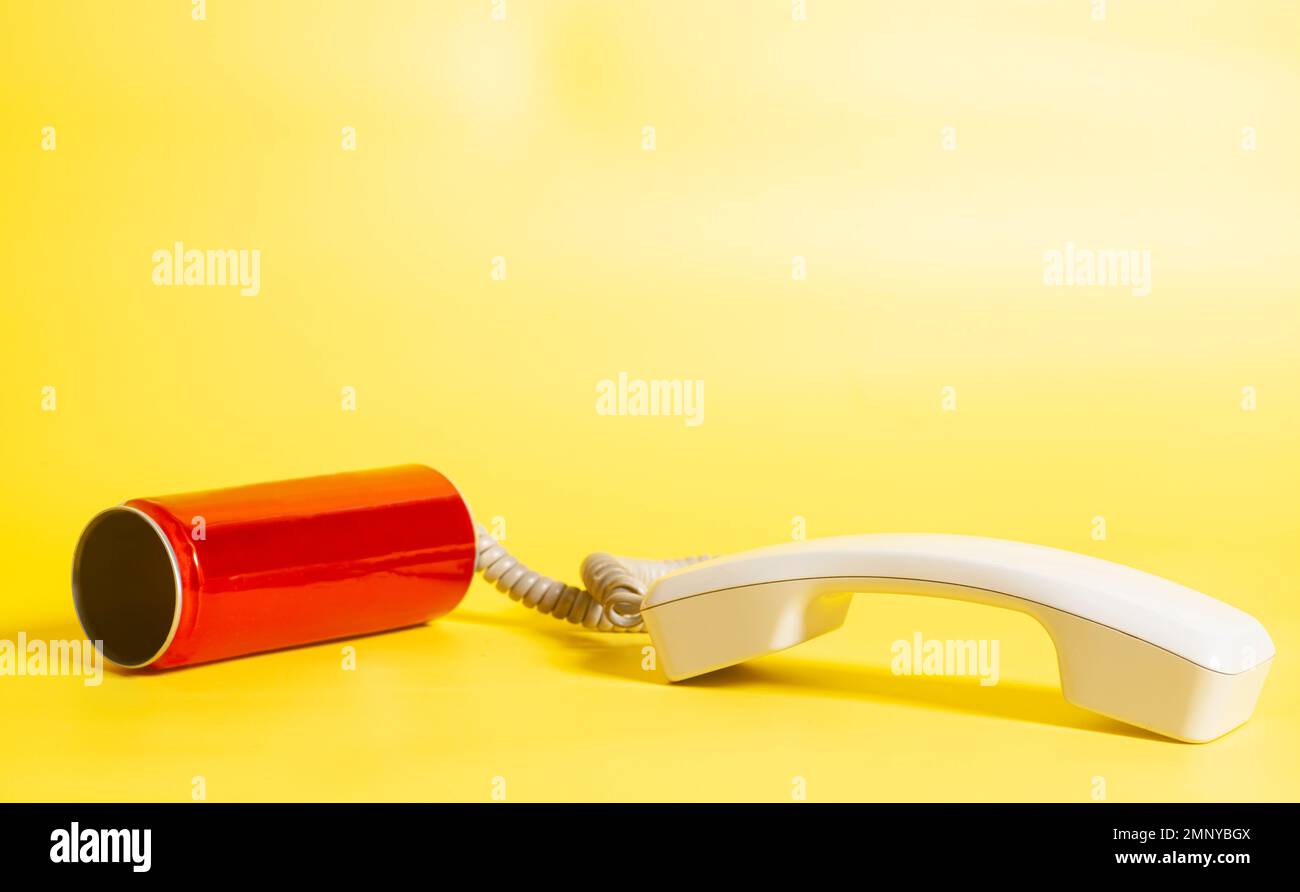 Tin can phone with handset on yellow background Stock Photo - Alamy