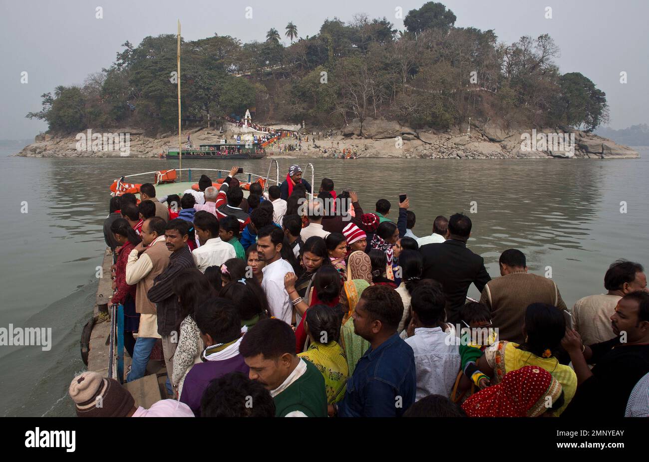 Devotees travel on a ferry to Umananda, left, a river island in the ...