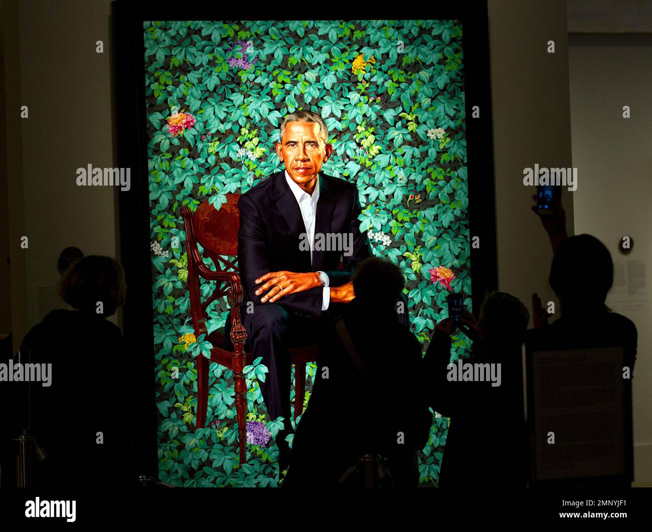 Visitors take pictures of the official portrait of the former President ...