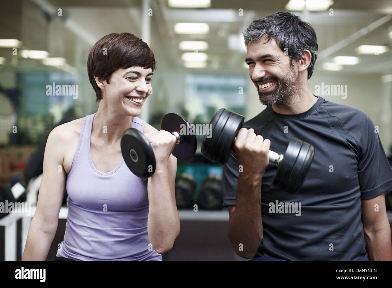 Do it together. two people working out using dumbbells in the gym Stock ...