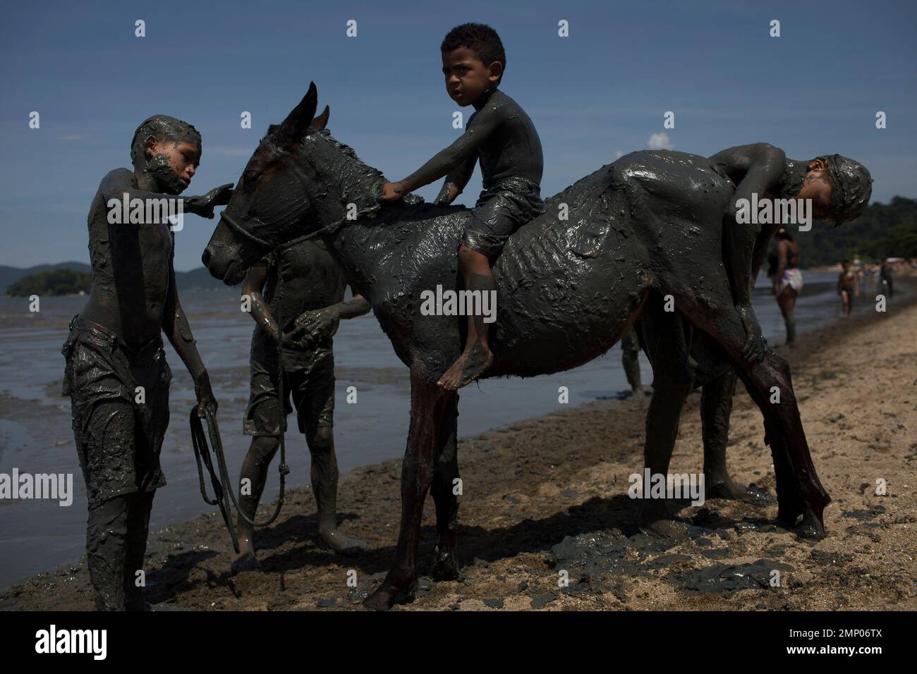 Kids cover a horse with mud as they take part in the traditional "Bloco ...