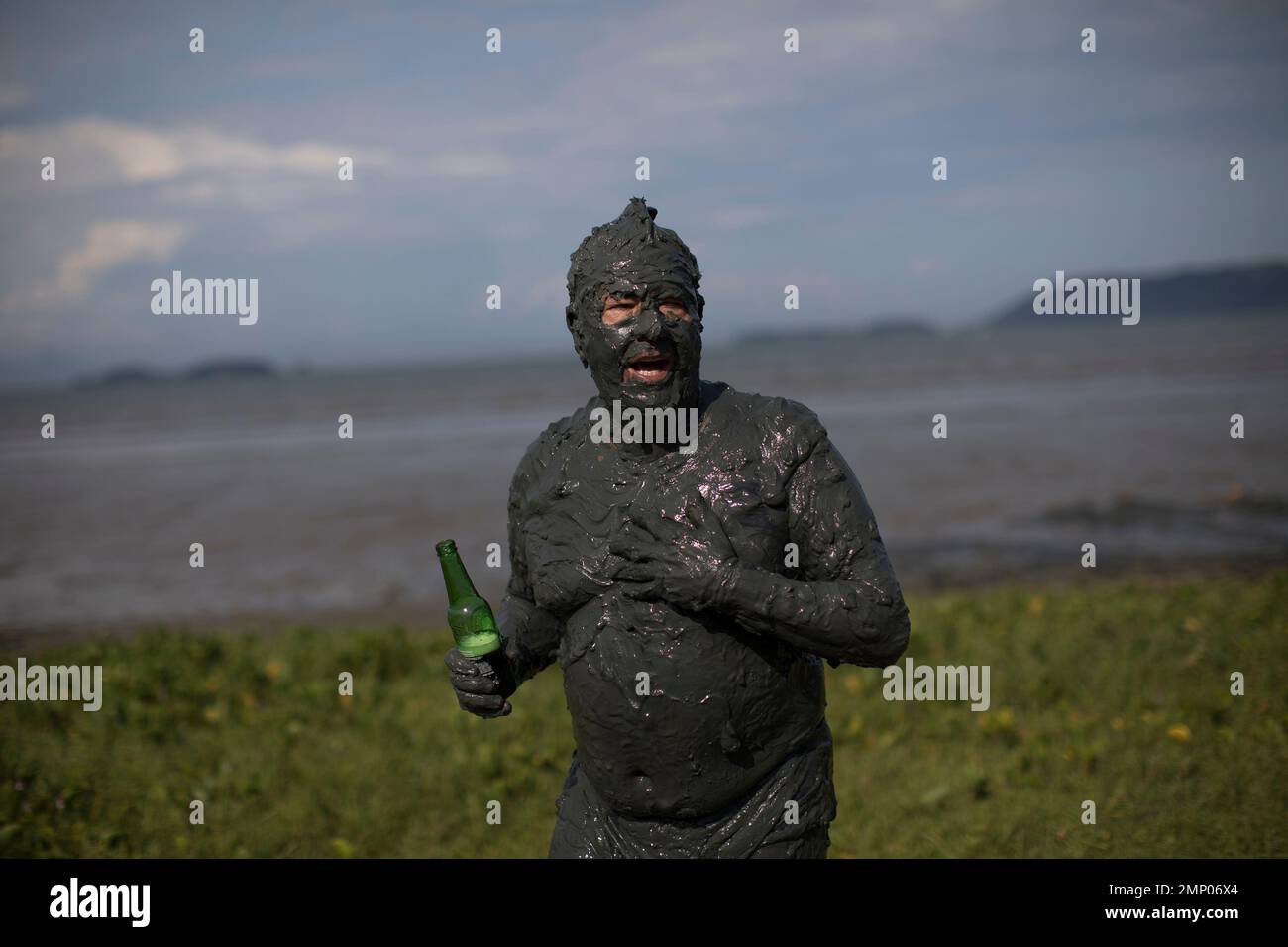 A mud covered reveler poses for a picture during the traditional "Bloco ...