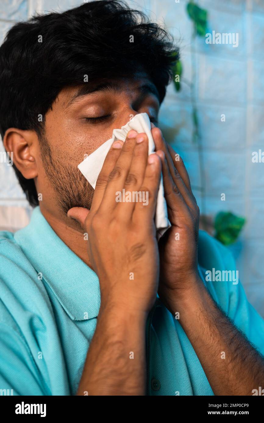 Vertical shot of sick man with sneezed using napkin during cold fever ...