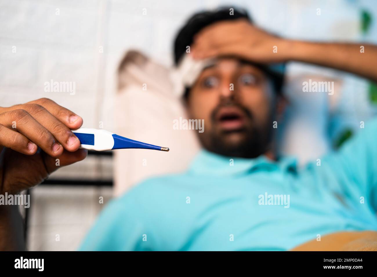 Shocked sick young man after seeing temperature during fever at home ...
