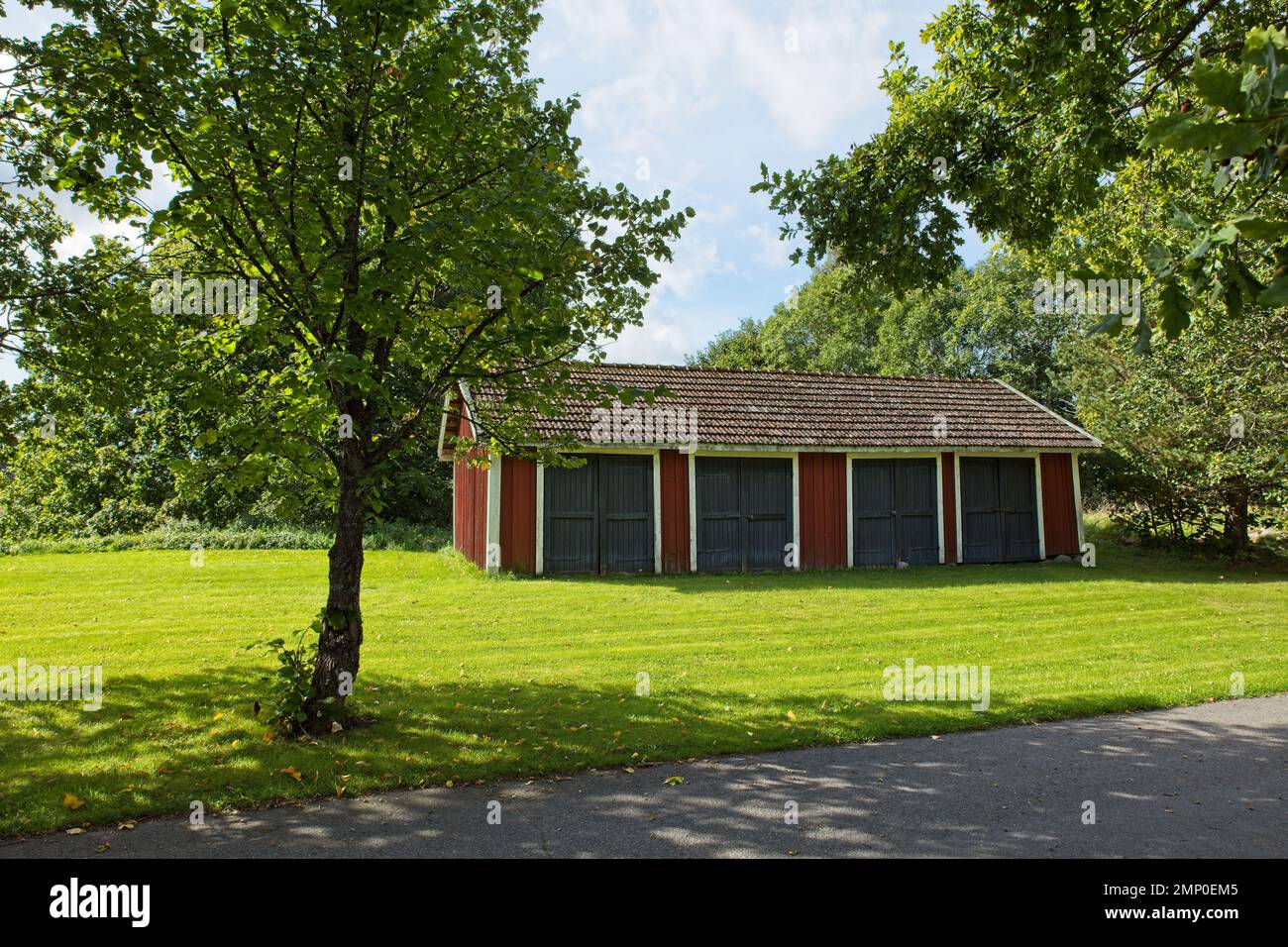 Red painted wooden barn and trees in summer Stock Photo - Alamy