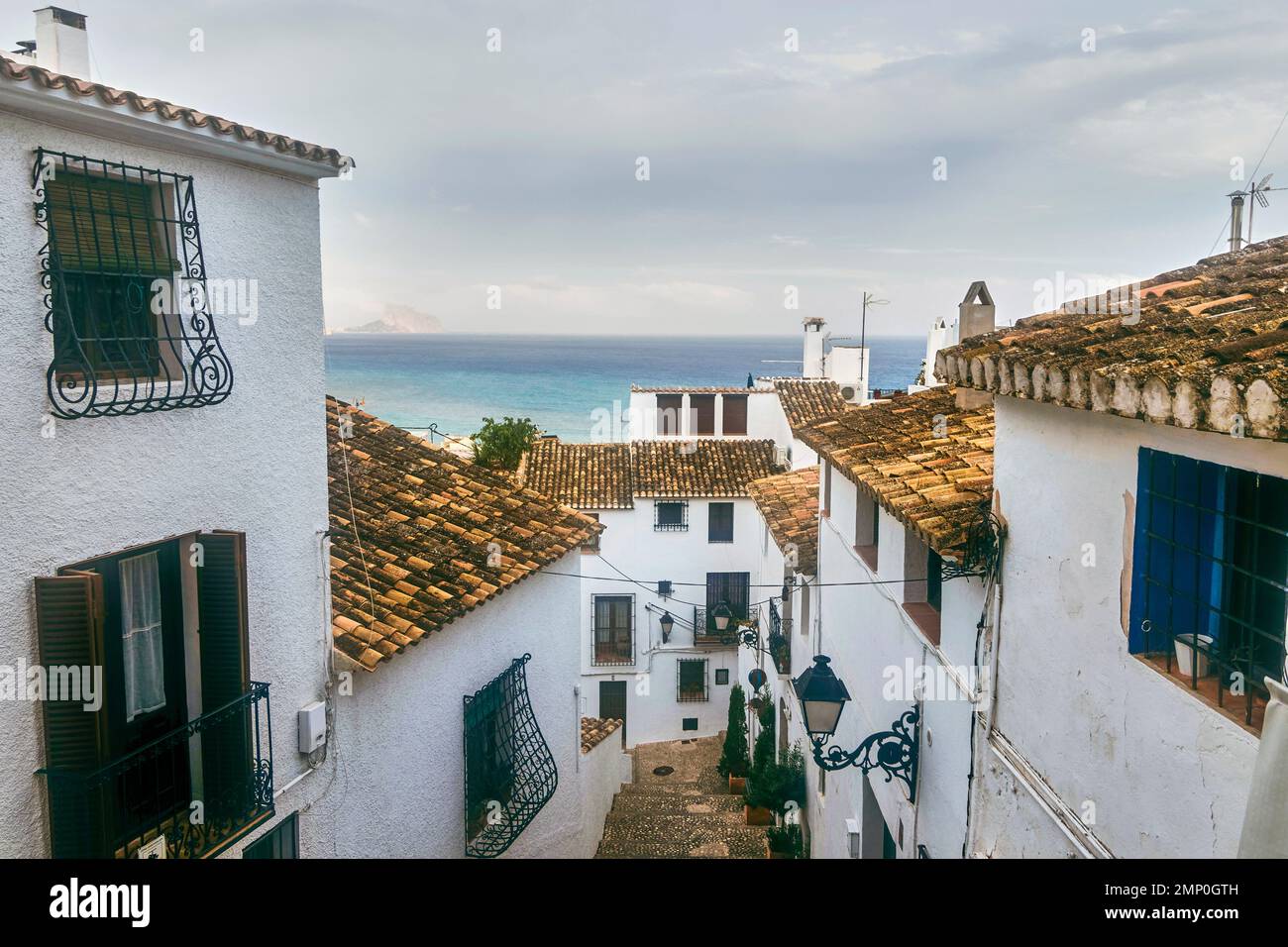 Beautiful alley with white houses in the town of Altea. The sea and the ...
