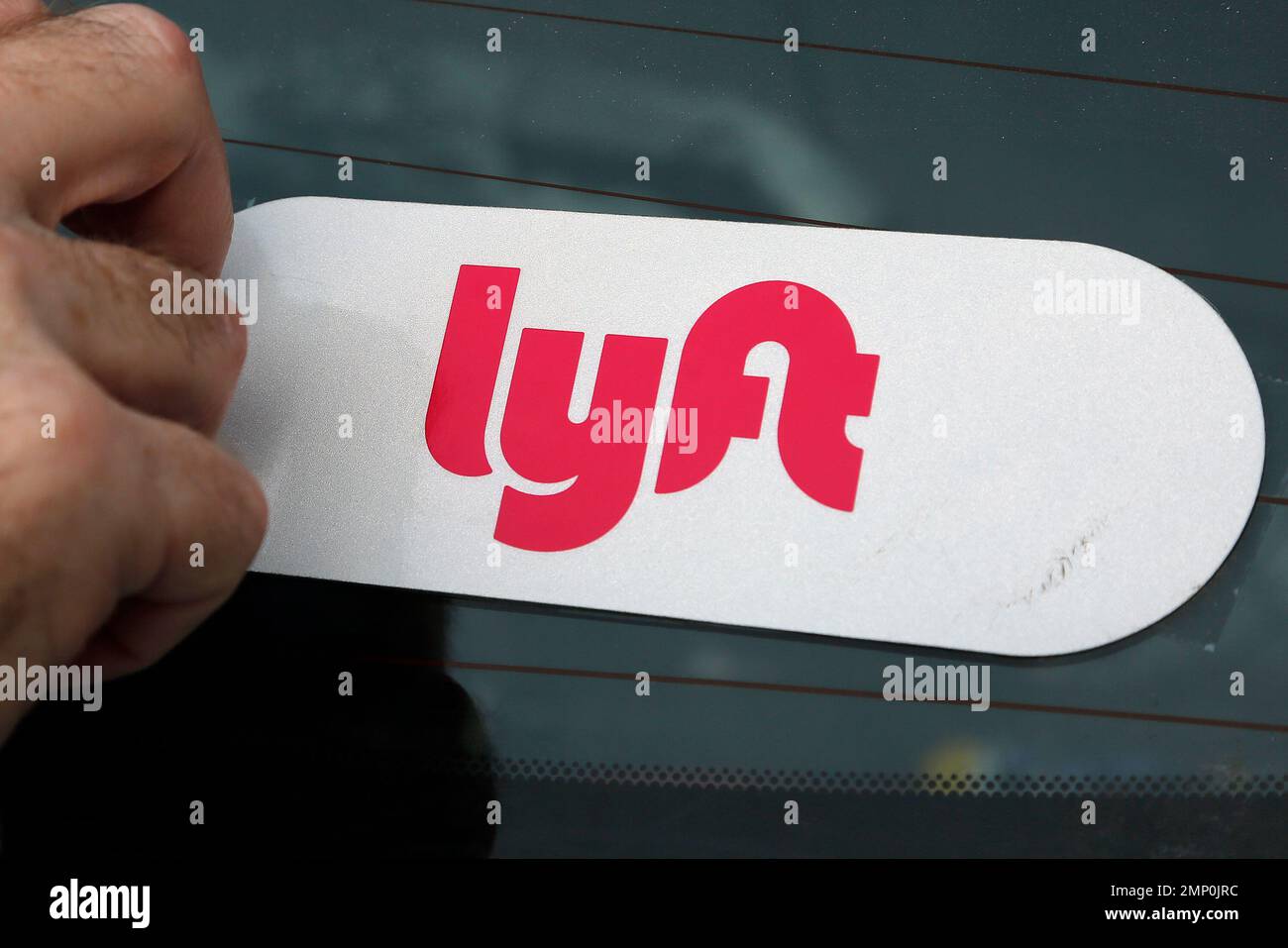 This is a Lyft logo being installed on a Lyft driver's car on Wednesday ...