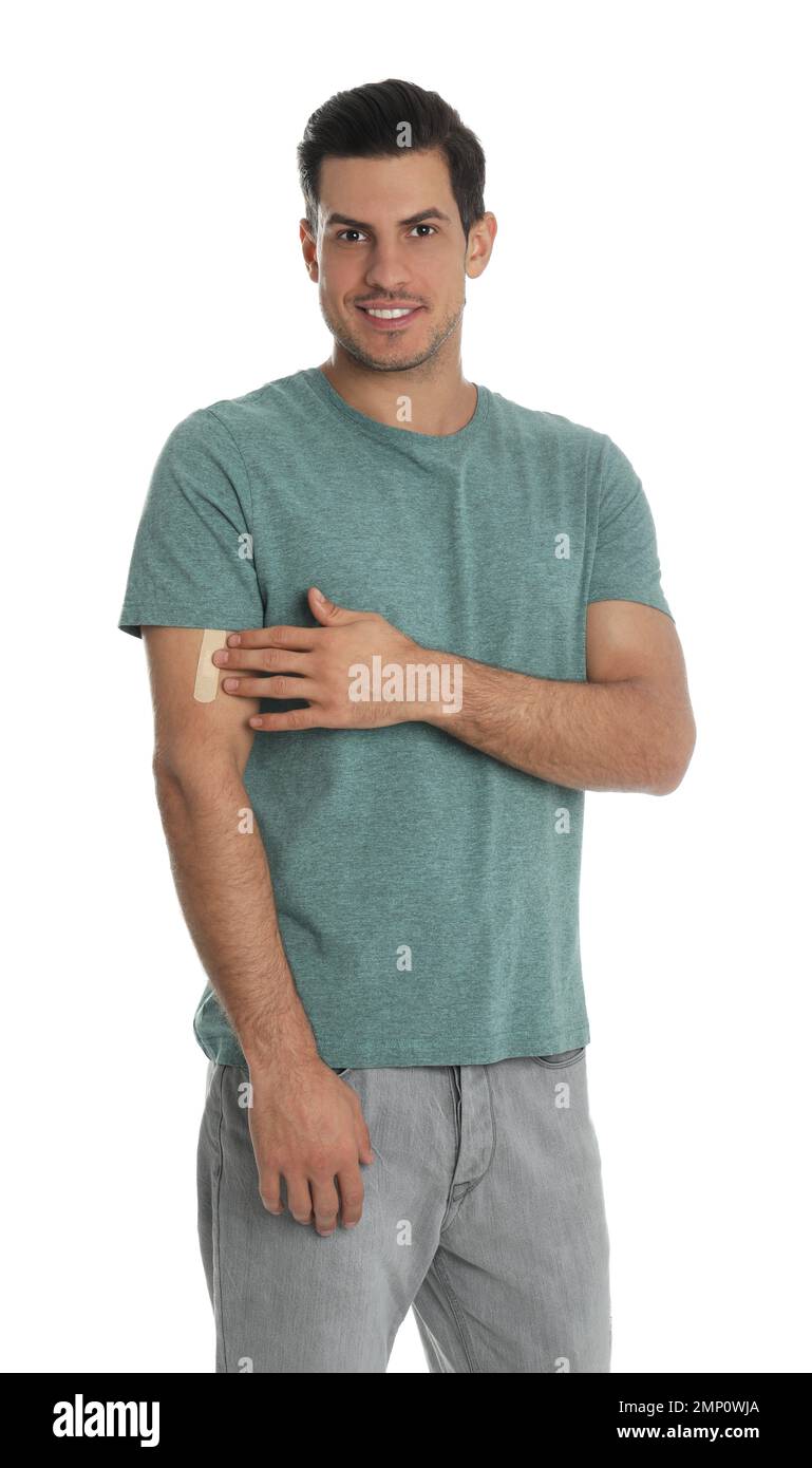 Happy man with sticking plaster on arm against white background Stock ...