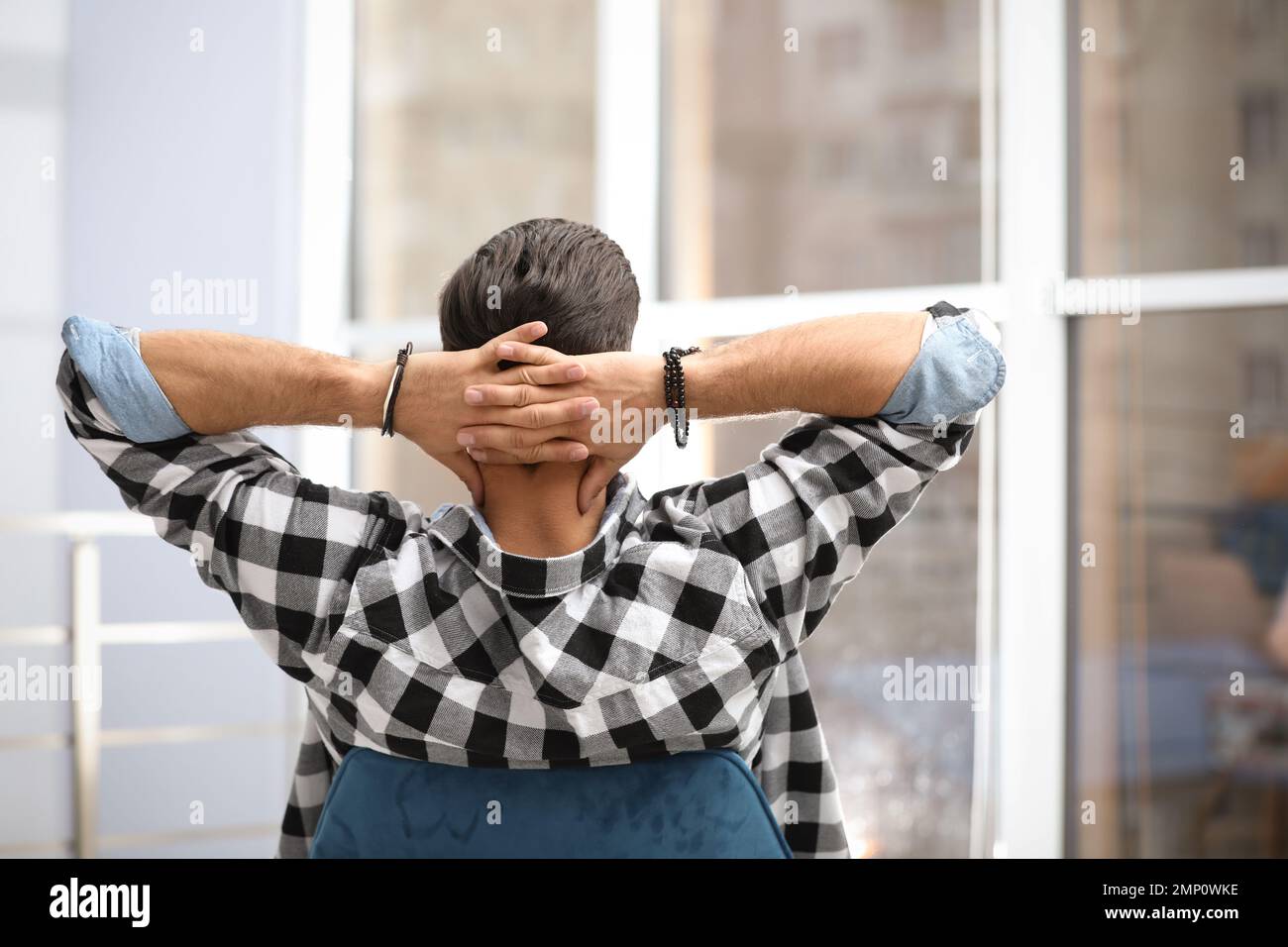 Man resting in armchair near window at home, back view Stock Photo - Alamy