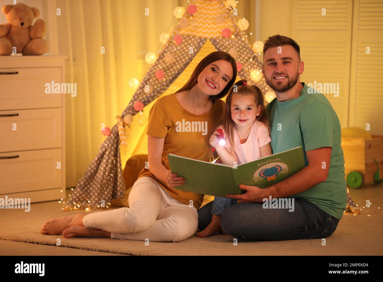 Family with flashlight reading book at home Stock Photo - Alamy