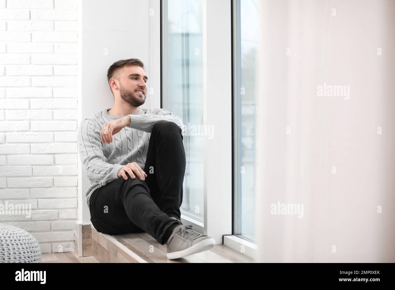 Handsome young man near window at home Stock Photo - Alamy