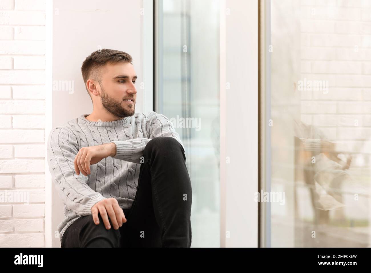 Handsome young man near window at home Stock Photo - Alamy
