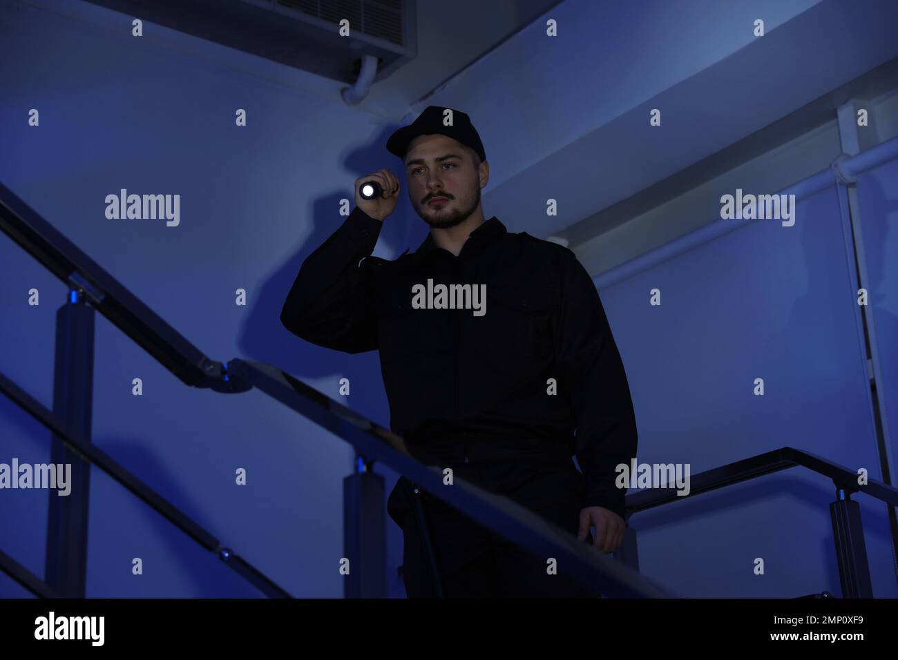 Male security guard with flashlight on stairs in darkness Stock Photo ...