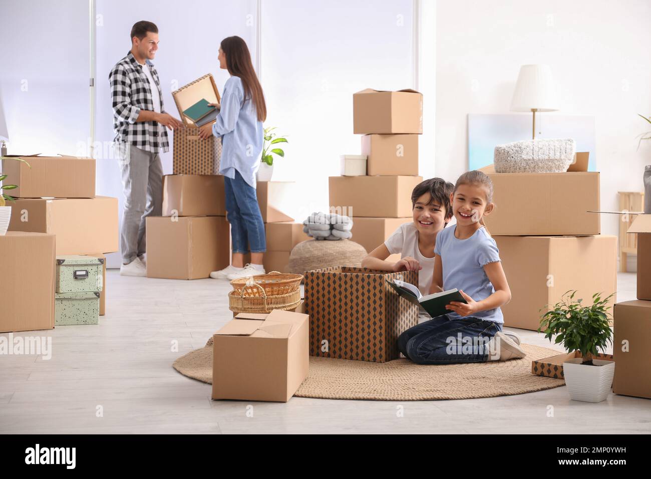 Happy family unpacking moving boxes at their new home Stock Photo - Alamy