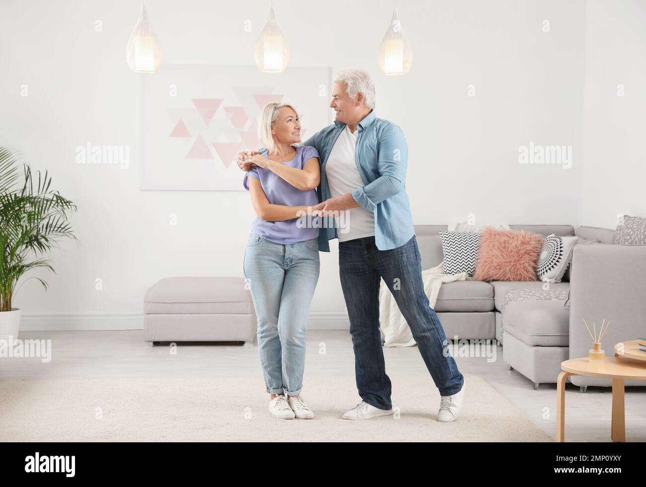 Happy mature couple dancing together in living room Stock Photo - Alamy