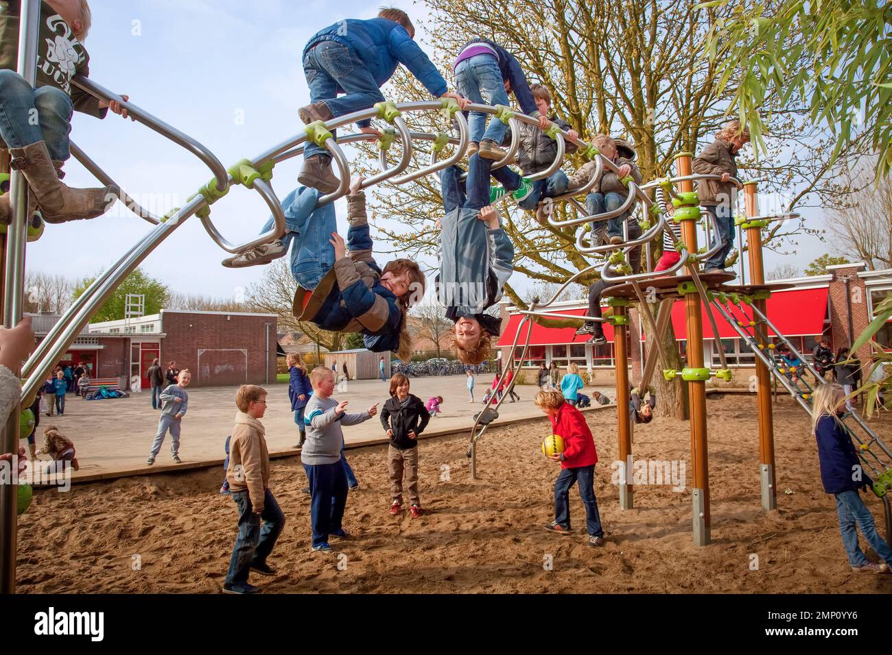 Netherlands, children play in school's playground with sand underneath ...