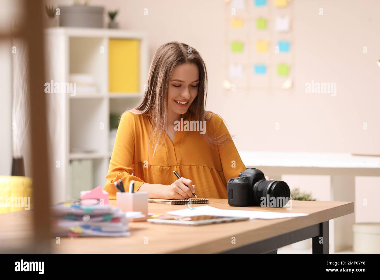 Young journalist with camera at table in office Stock Photo - Alamy