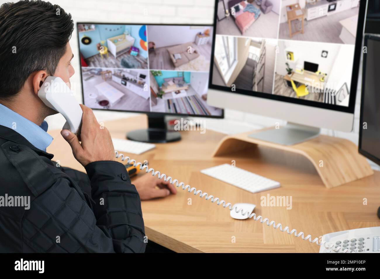 Male security guard talking by telephone near monitors at workplace ...