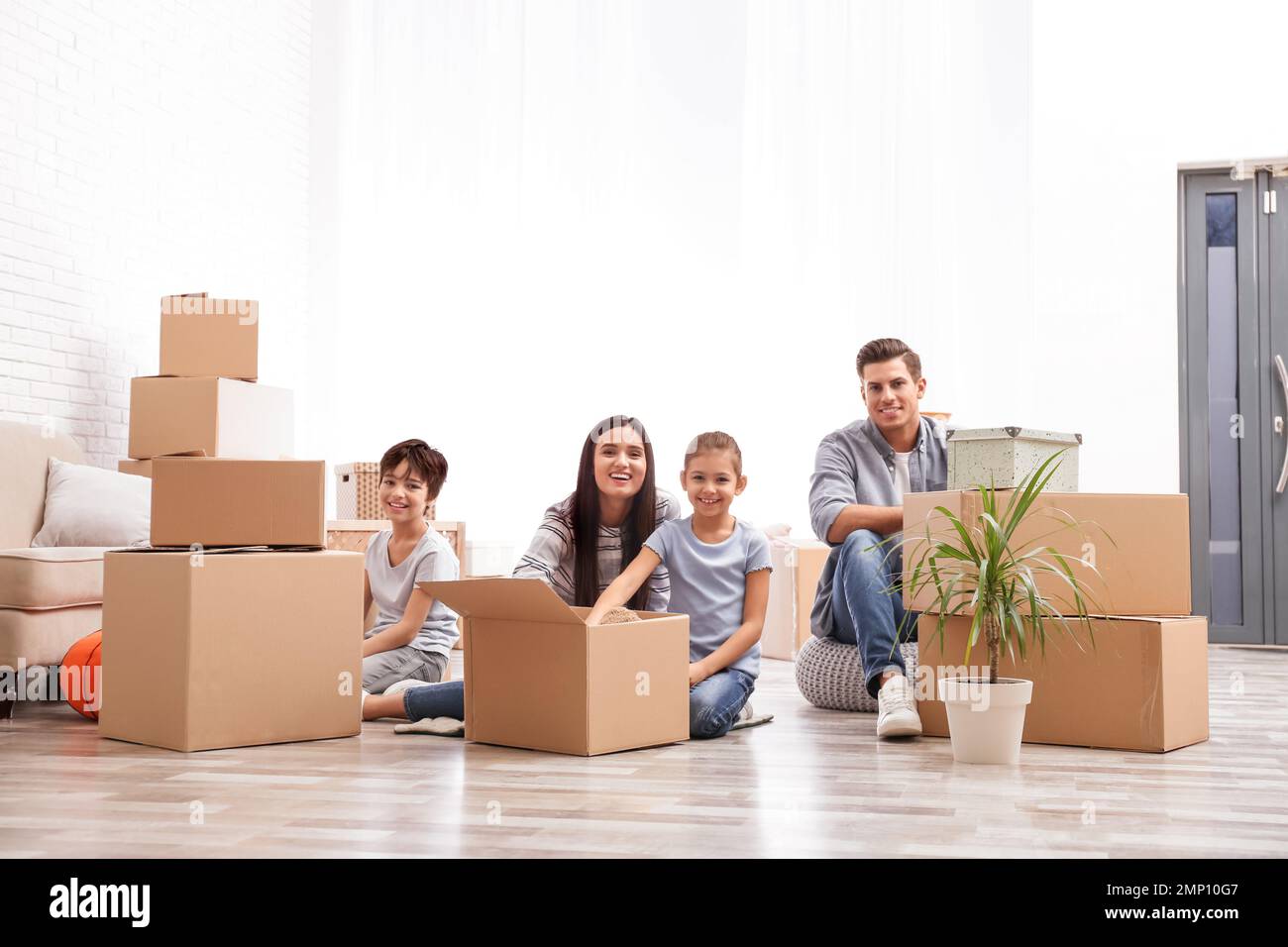 Happy family unpacking moving boxes at their new home Stock Photo - Alamy