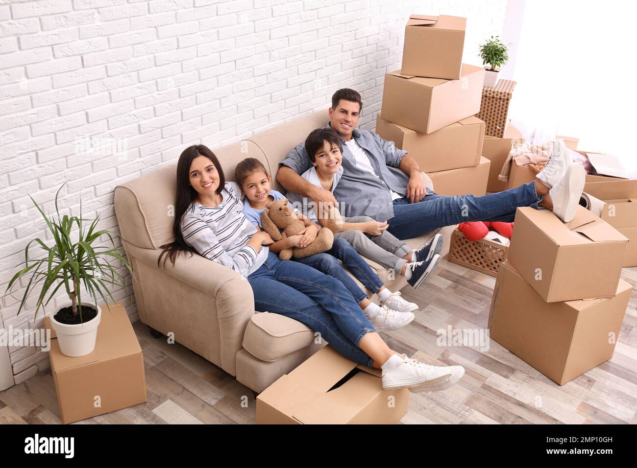 Happy family resting in room with cardboard boxes on moving day Stock ...