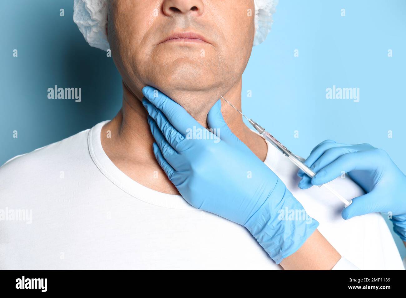 Mature man with double chin receiving injection on blue background ...