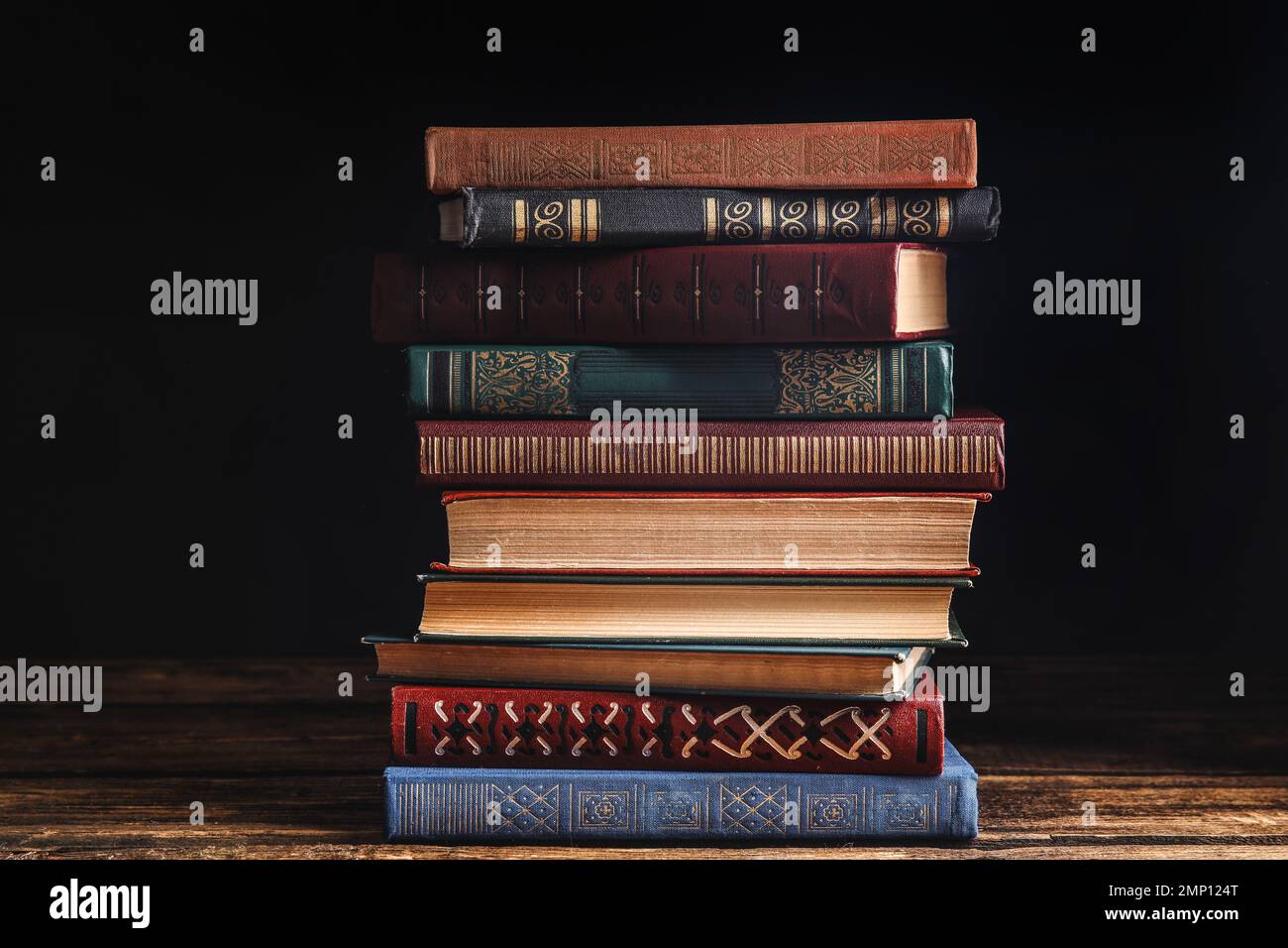 Collection of different books on wooden table against dark background ...