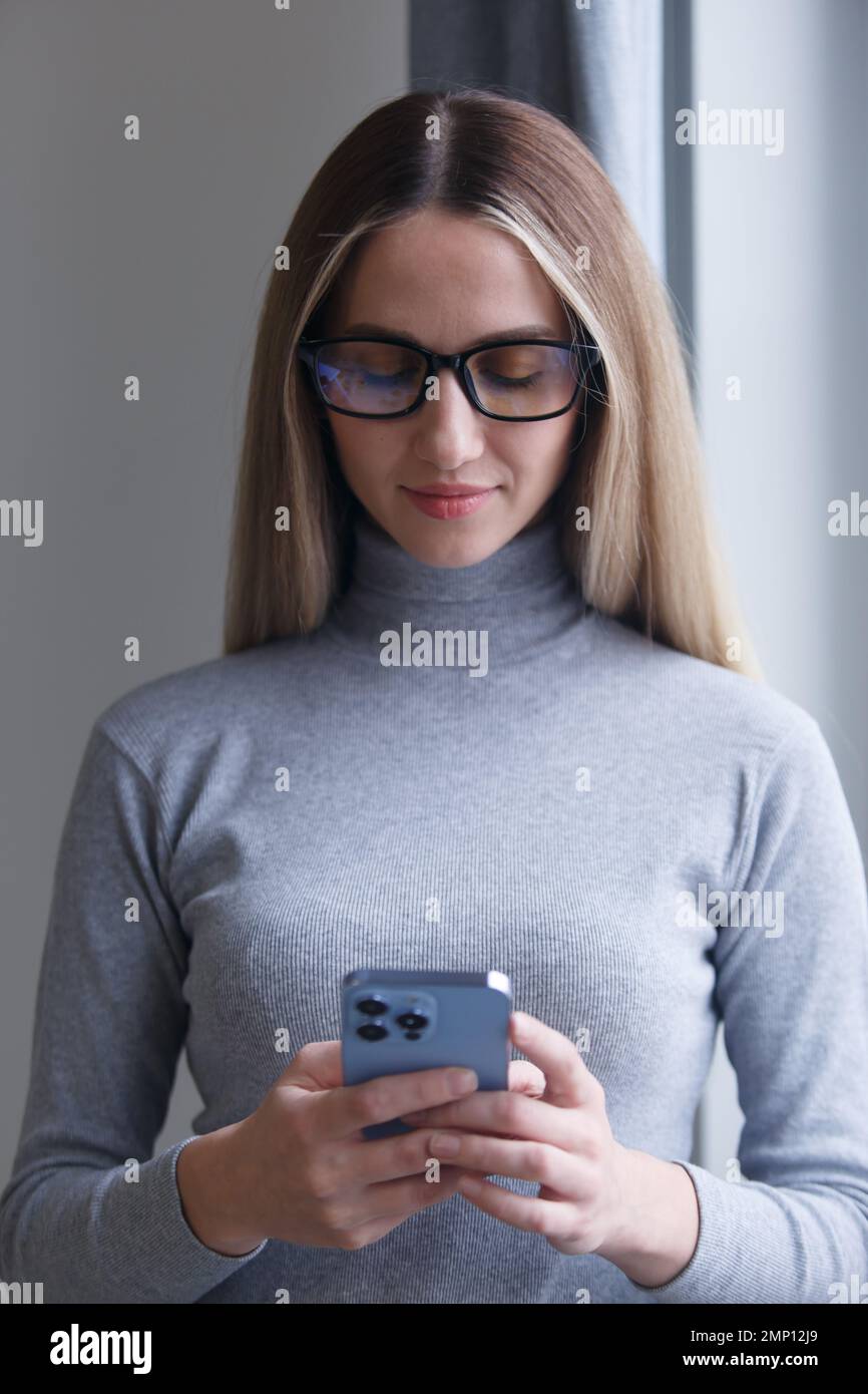 Portrait of beautiful blonde woman typing sms message on mobile phone ...