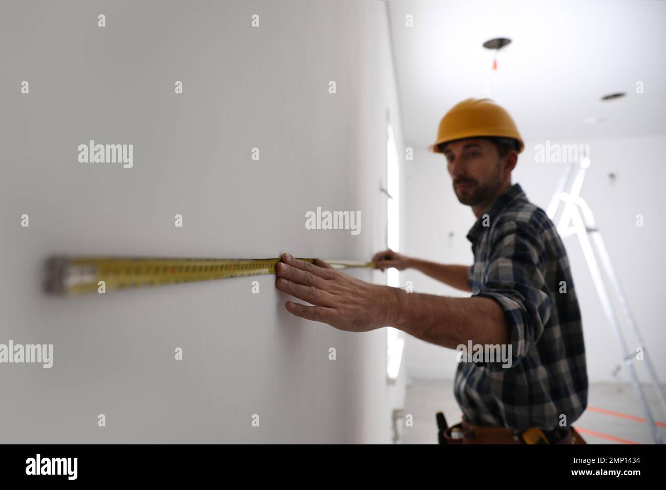 Worker measuring white wall indoors, focus on hand Stock Photo - Alamy