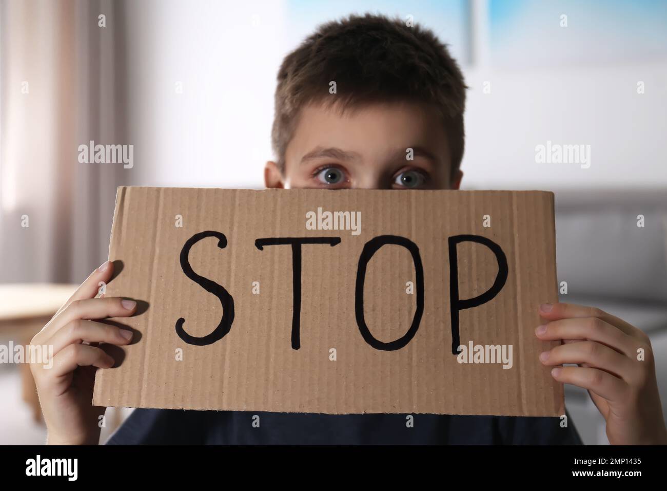 Abused little boy with sign STOP indoors. Domestic violence concept ...