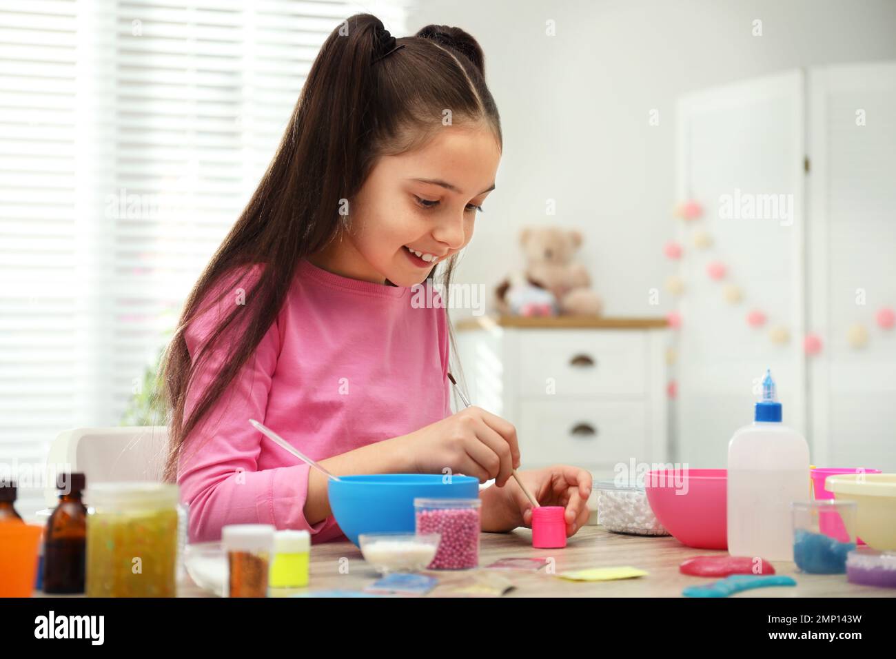 Cute little girl making homemade slime toy at table indoors Stock Photo ...
