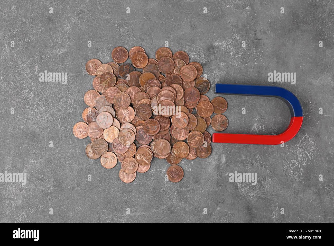 Magnet attracting coins on grey stone table, flat lay Stock Photo - Alamy
