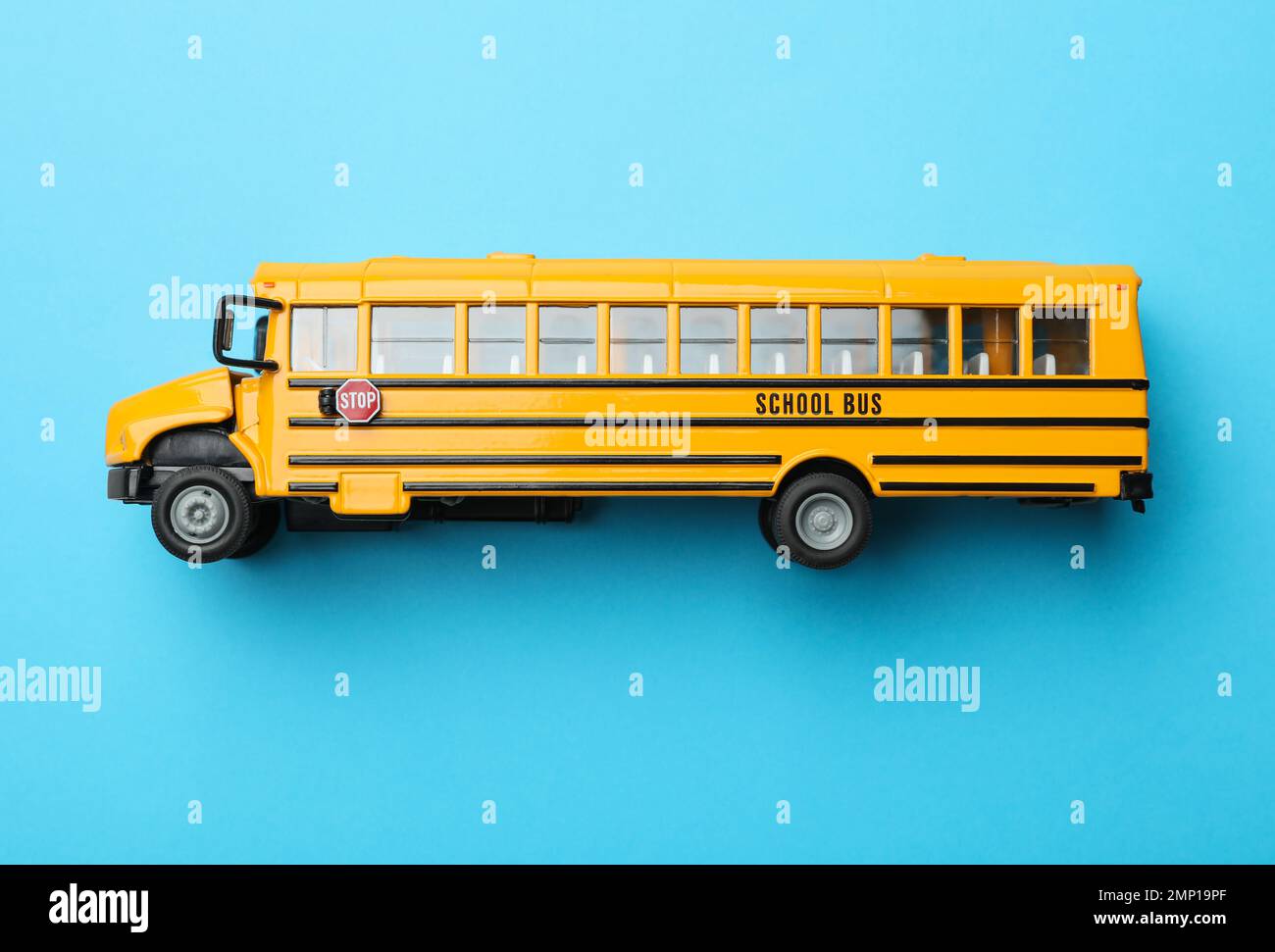 Yellow school bus on light blue background, top view. Transport for ...