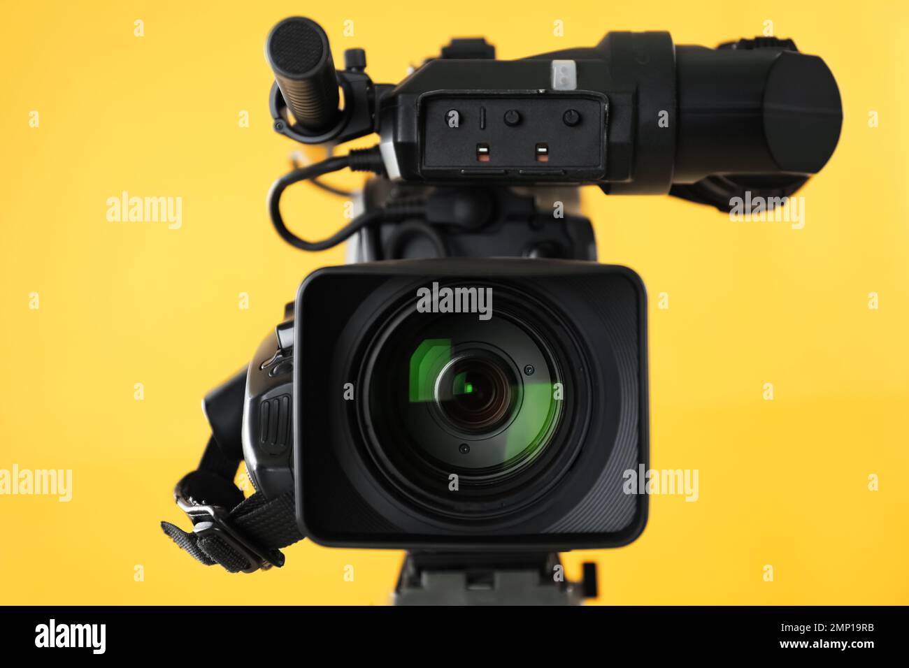 Modern professional video camera on yellow background, closeup Stock ...