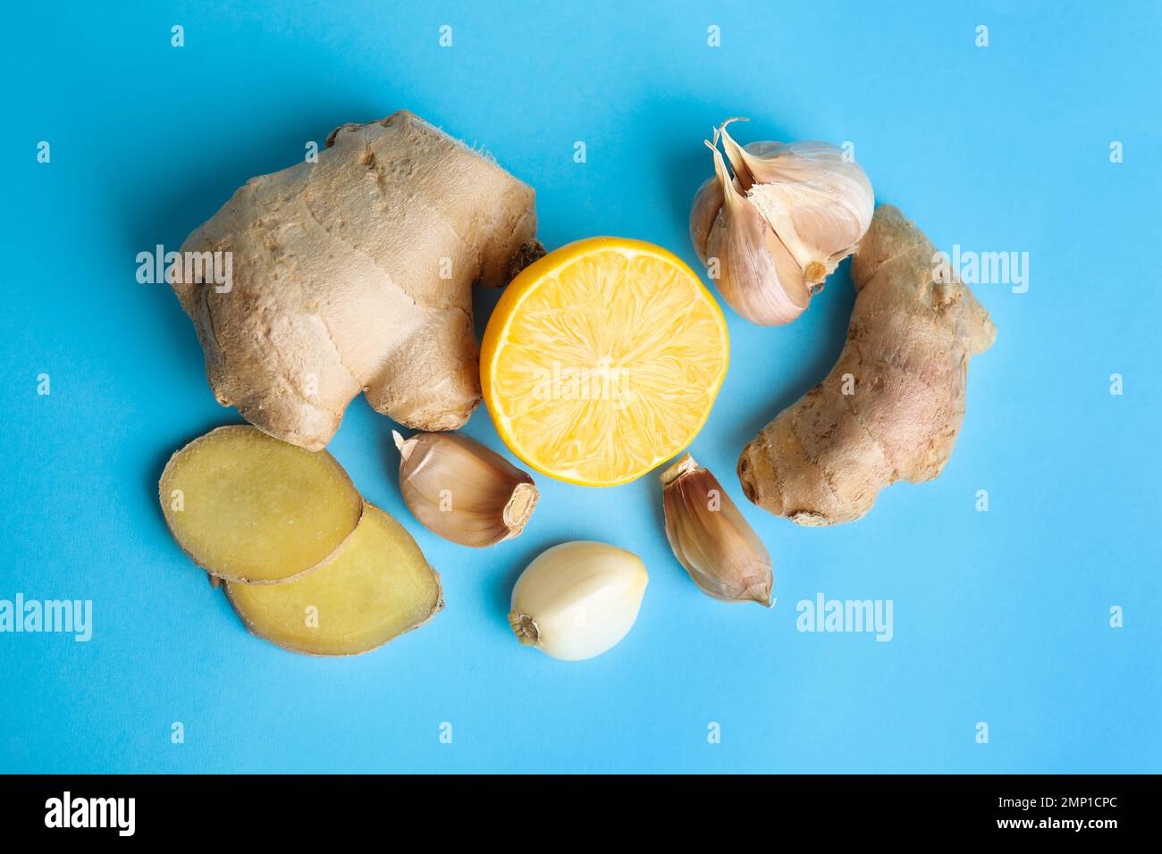 Fresh garlic and other natural cold remedies on light blue background ...