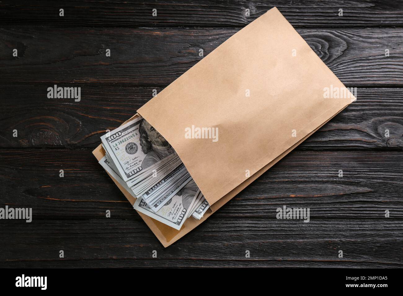 Envelope with dollar bills on black wooden table, top view. Bribe ...