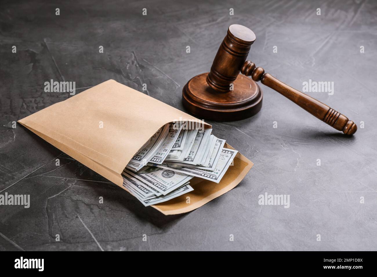 Dollar bills in envelope and gavel on grey stone table. Bribe concept ...