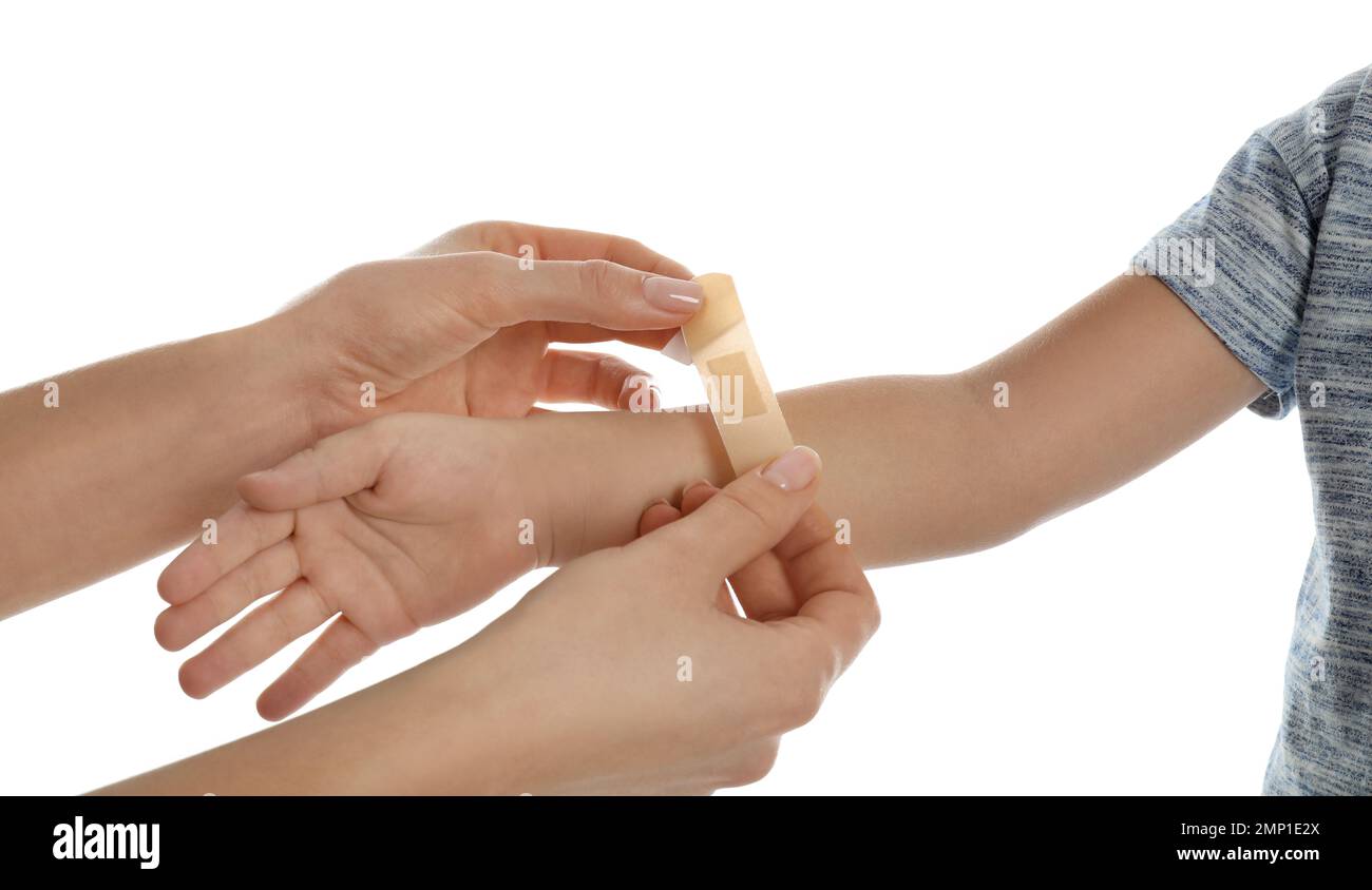 Mother putting sticking plaster onto son's arm on white background ...