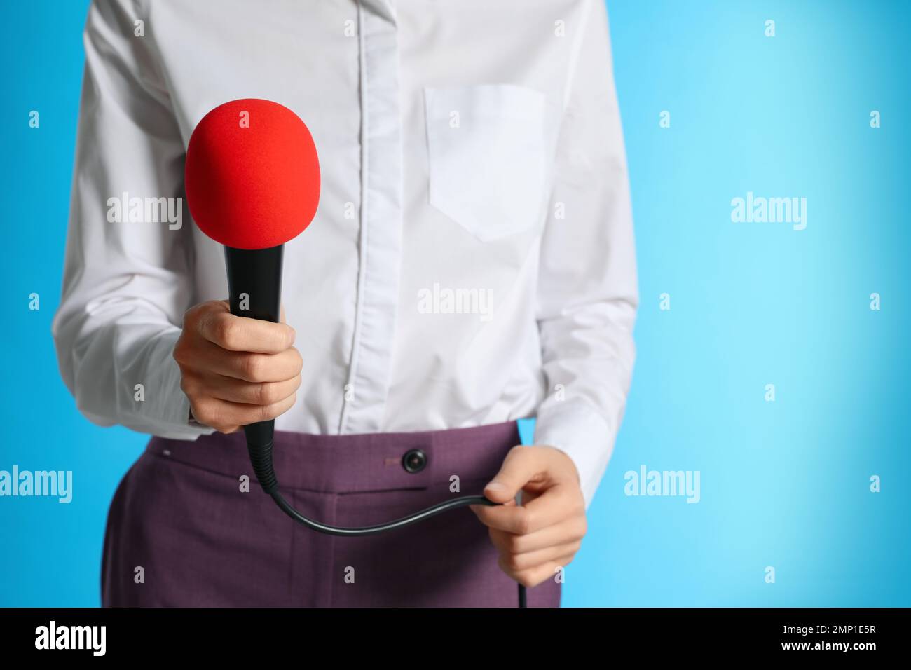Professional journalist with microphone on light blue background ...