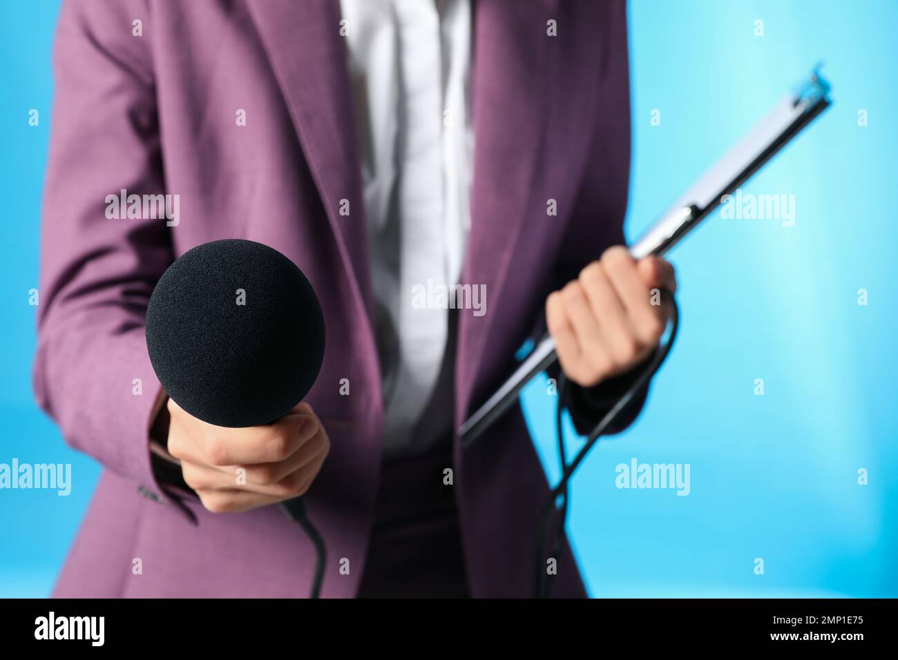 Professional journalist with clipboard and microphone on light blue ...