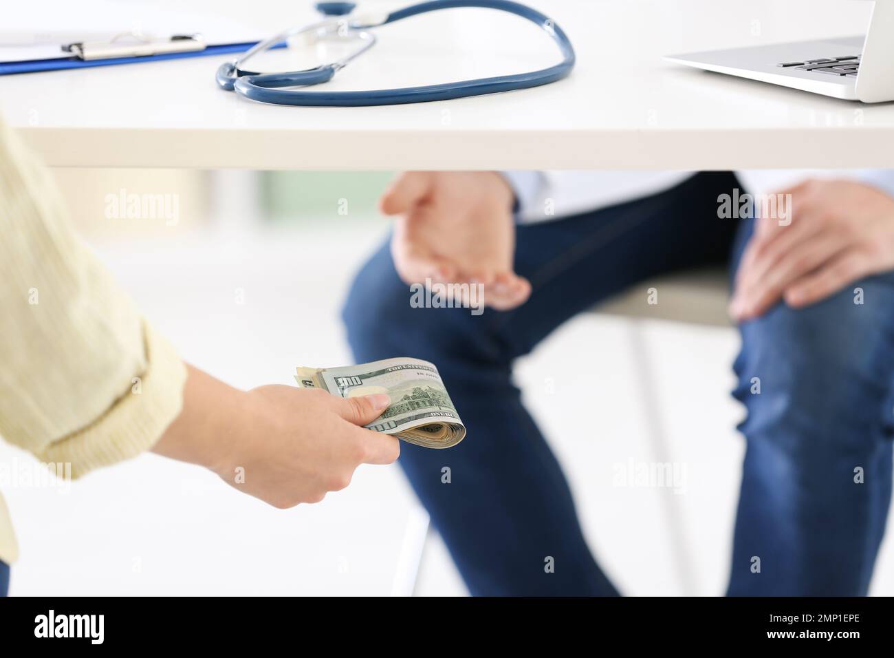 Patient giving bribe to doctor under table in clinic, closeup ...