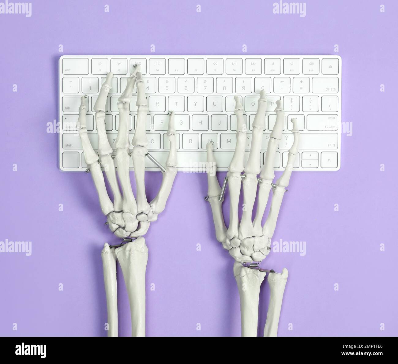 Human skeleton using computer keyboard on violet background, top view ...