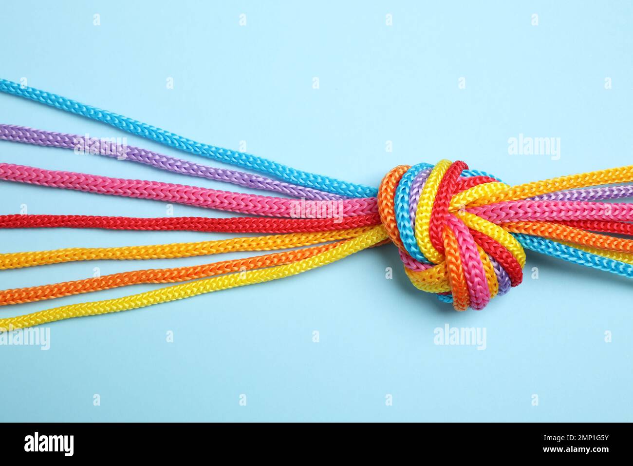 Colorful ropes tied together on light blue background, top view. Unity ...