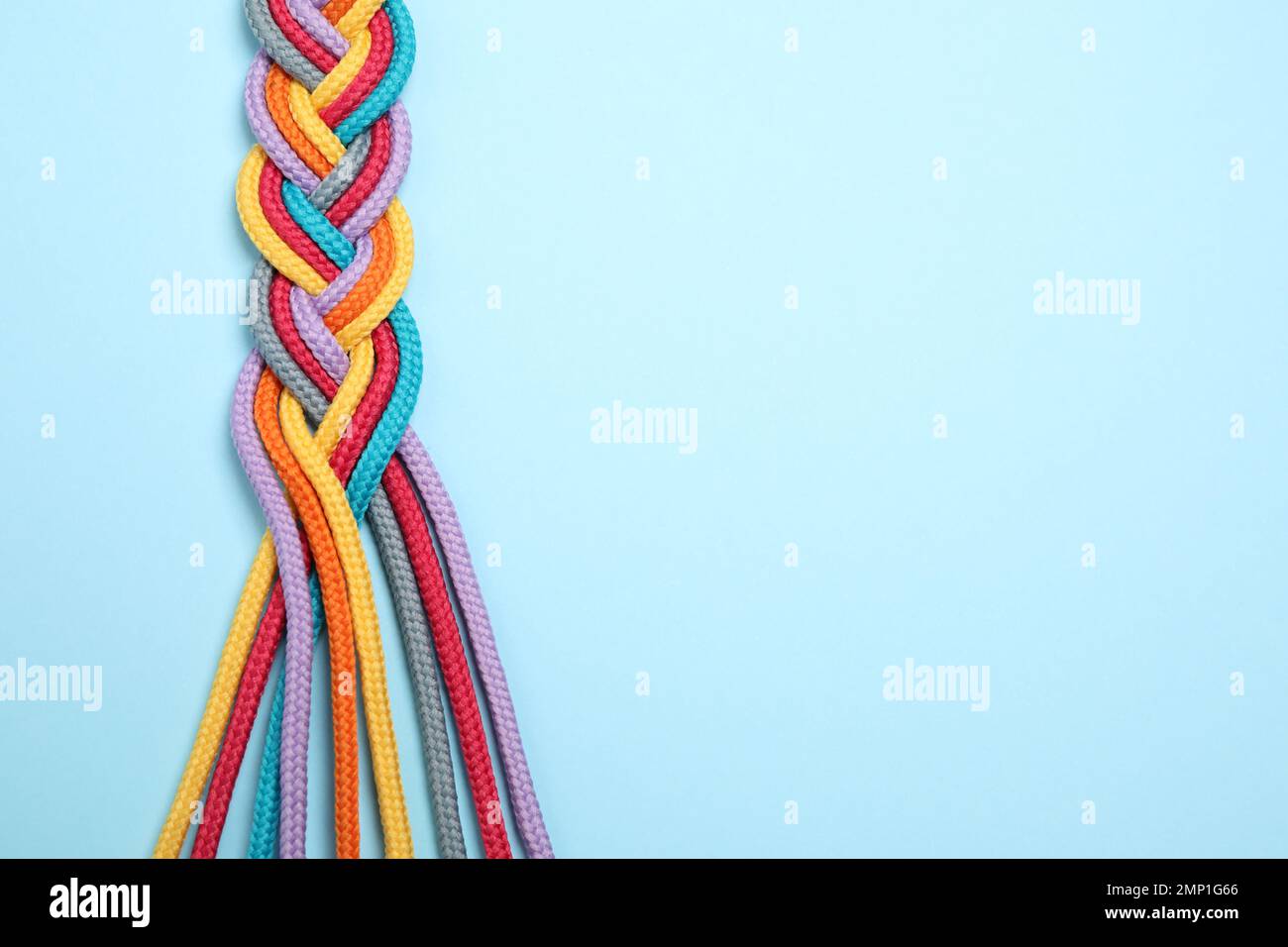 Top view of braided colorful ropes on light blue background, space for ...