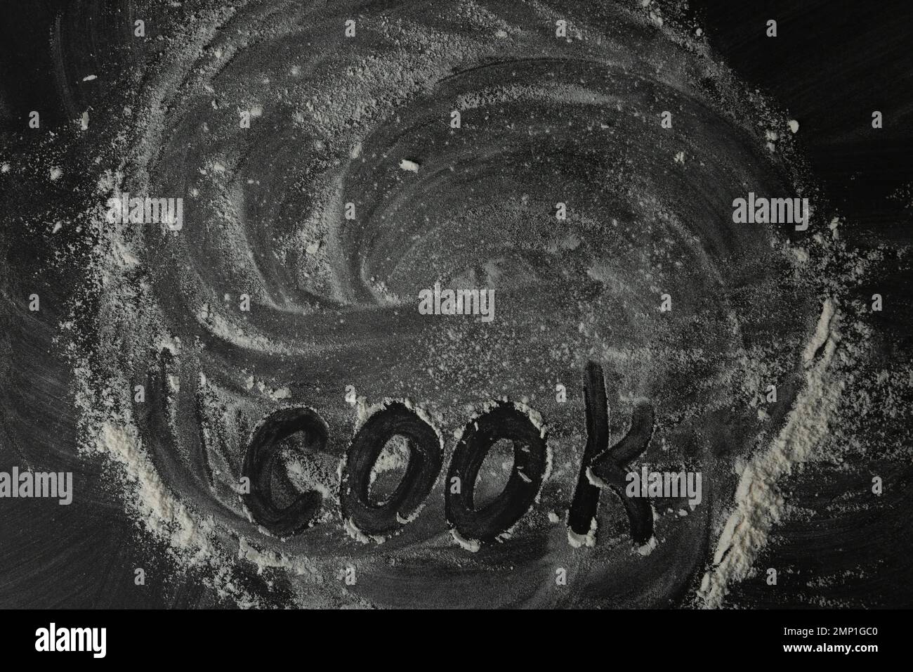 White flour and word COOK on black table, top view. Space for text ...