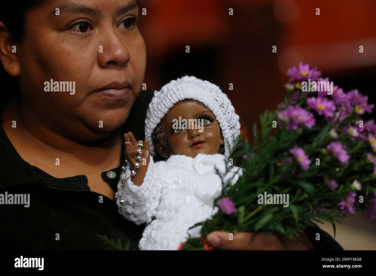 A woman holds her baby Jesus figurine inside the San Juan Bautista ...