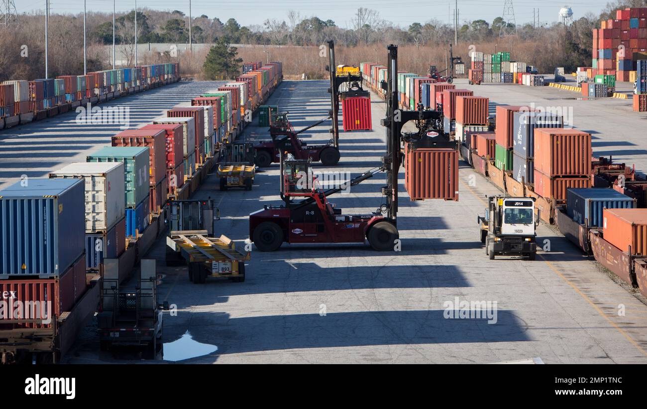 Three top-lifts moves a shipping container from rail cars to a jockey ...